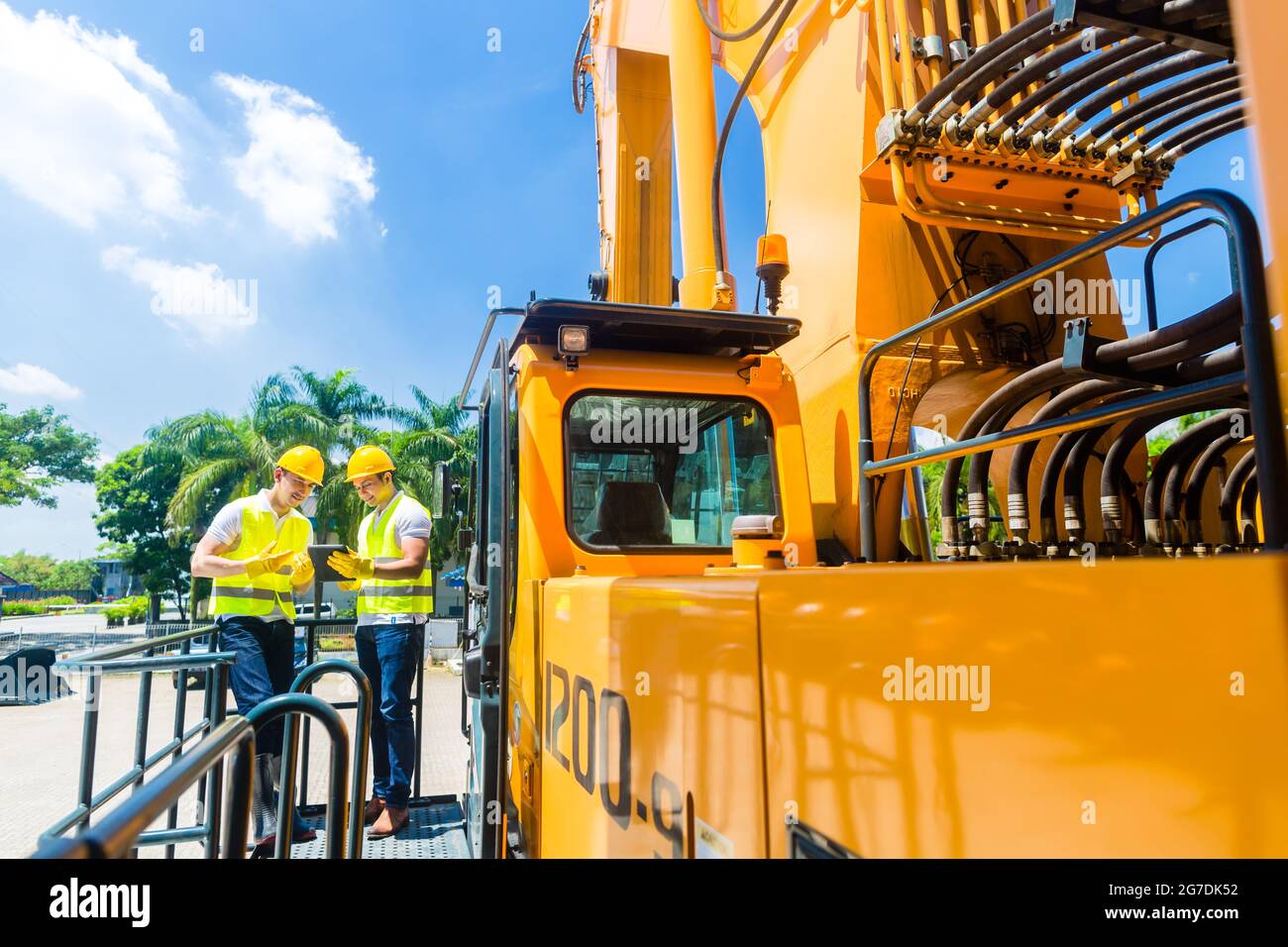 Asian construction machinery driver discussing with foreman blueprints ...
