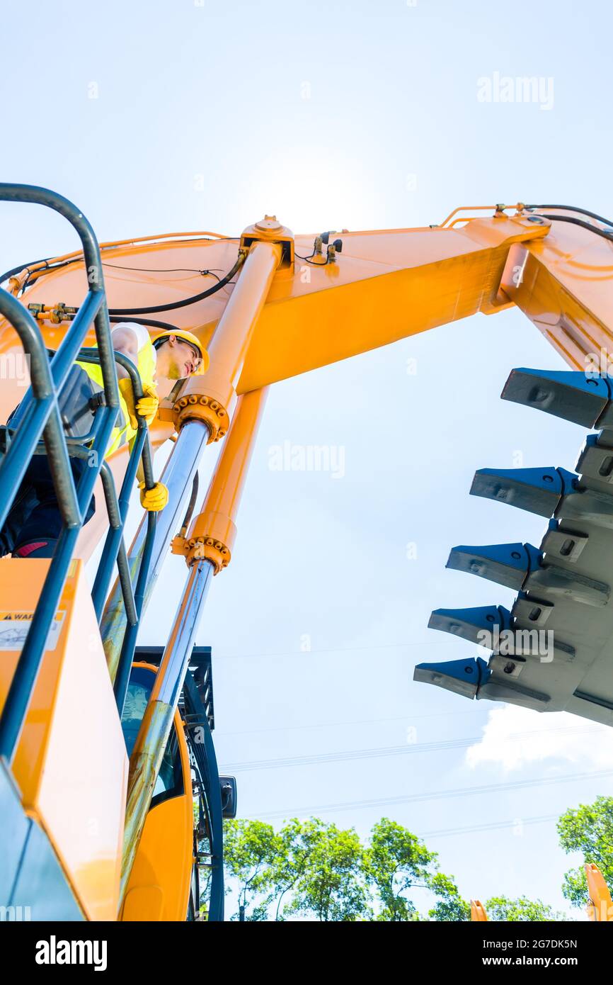 Asian driver standing on construction machinery on building site Stock ...