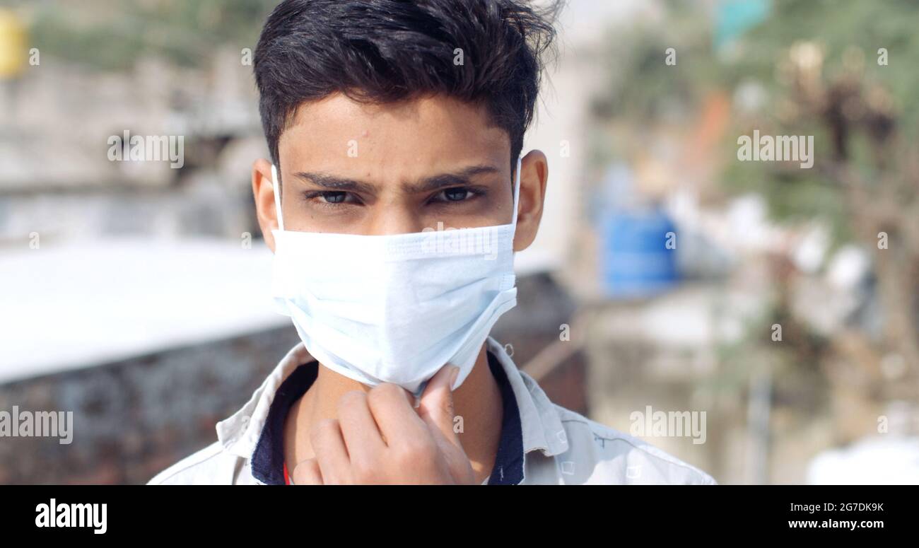 Young Indian boy posing with his hand on his chin while wearing a white ...