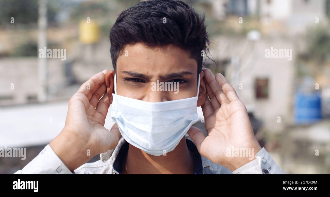 Closeup of a young Indian boy wearing a Covid mask and touching his ...