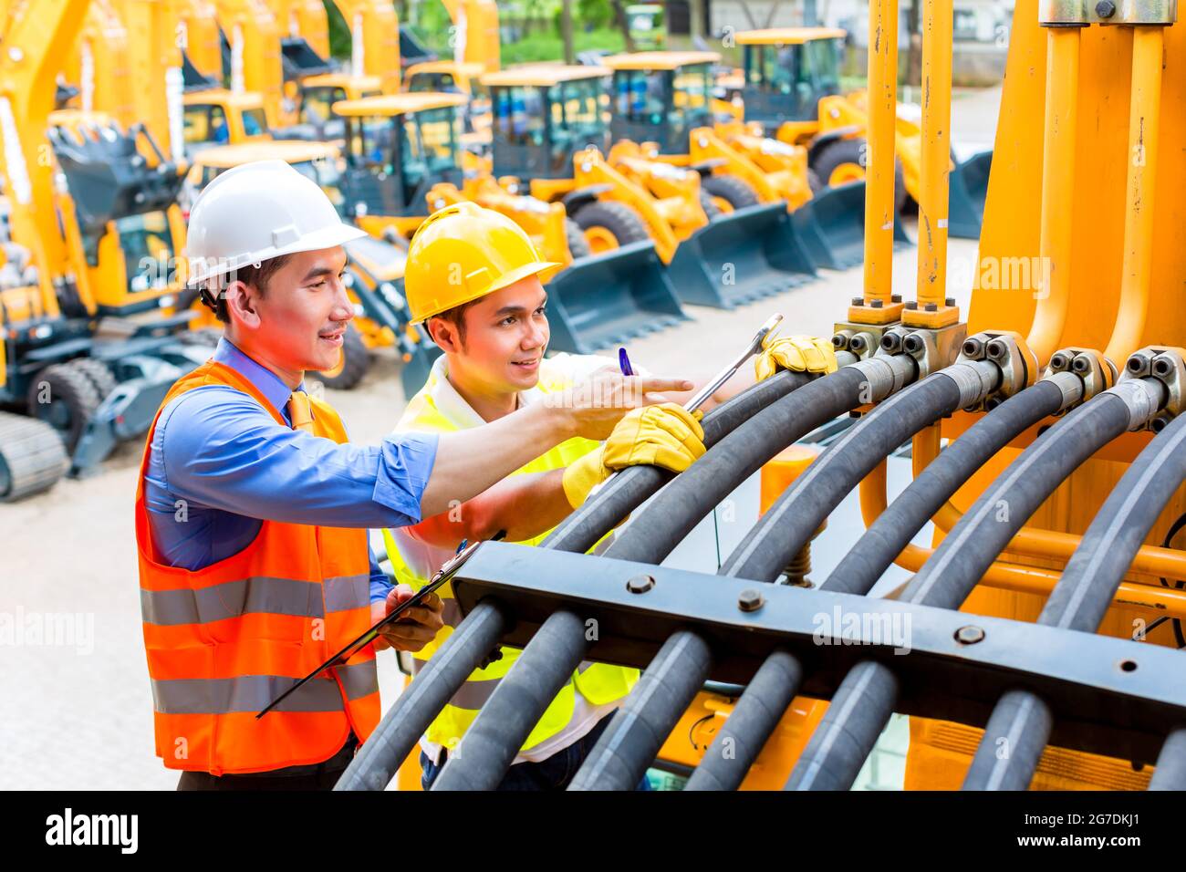 Asian motor mechanic discussing with engineer task list in construction machine workshop Stock ...