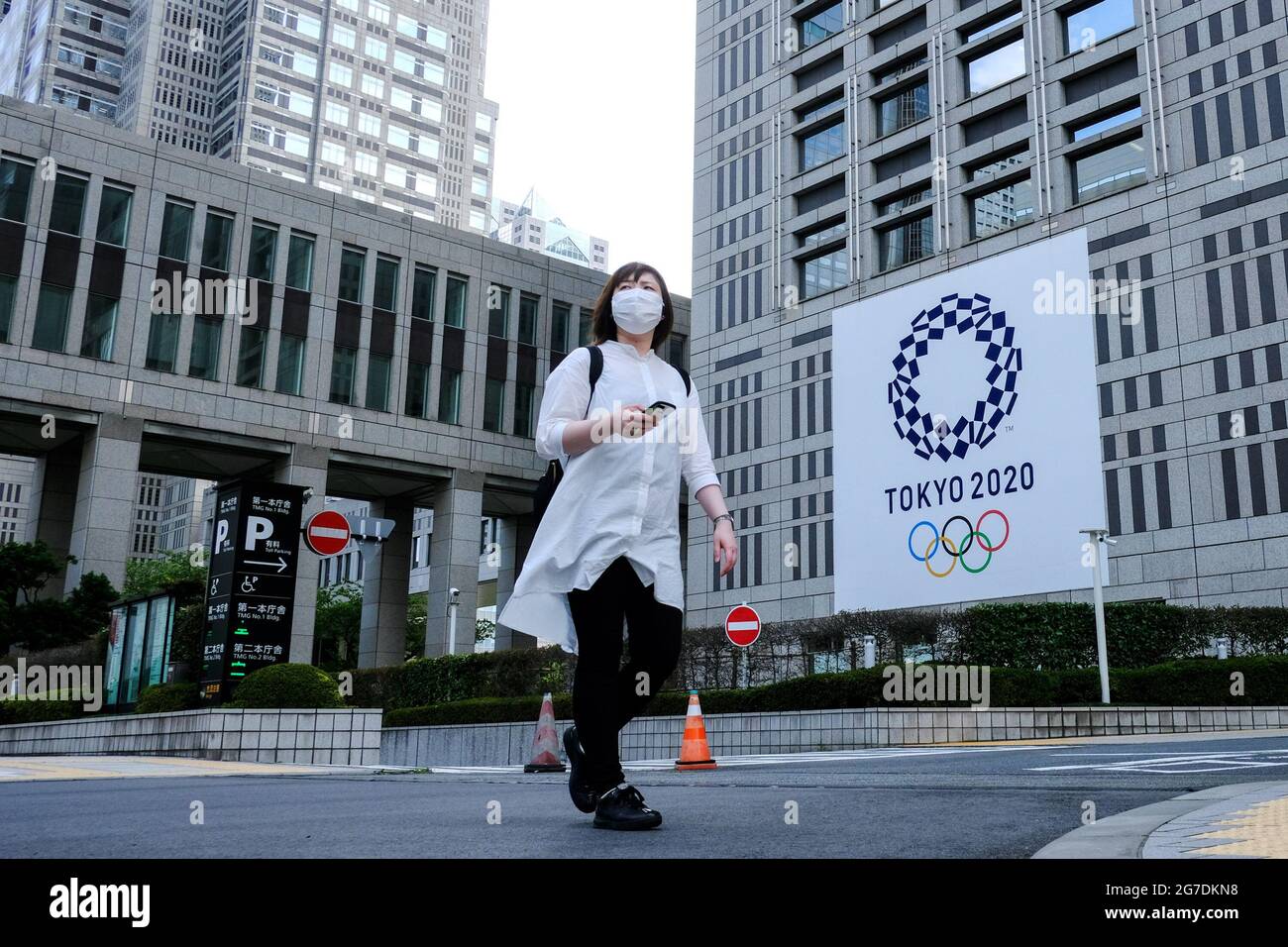 A woman wearing a mask walks past a Tokyo 2020 Olympics banner at the ...
