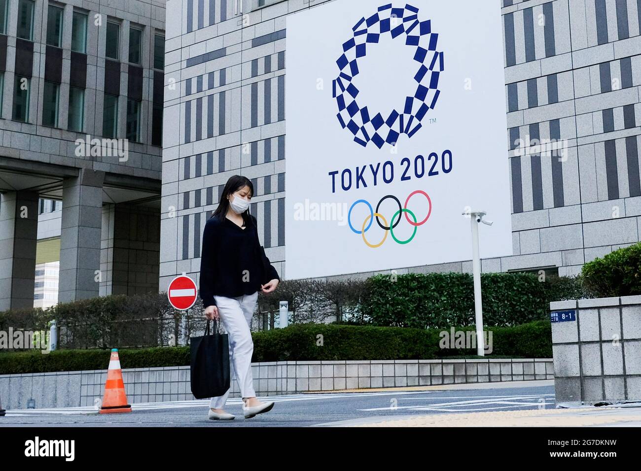 A woman wearing a mask walks past a Tokyo 2020 Olympics banner at the ...