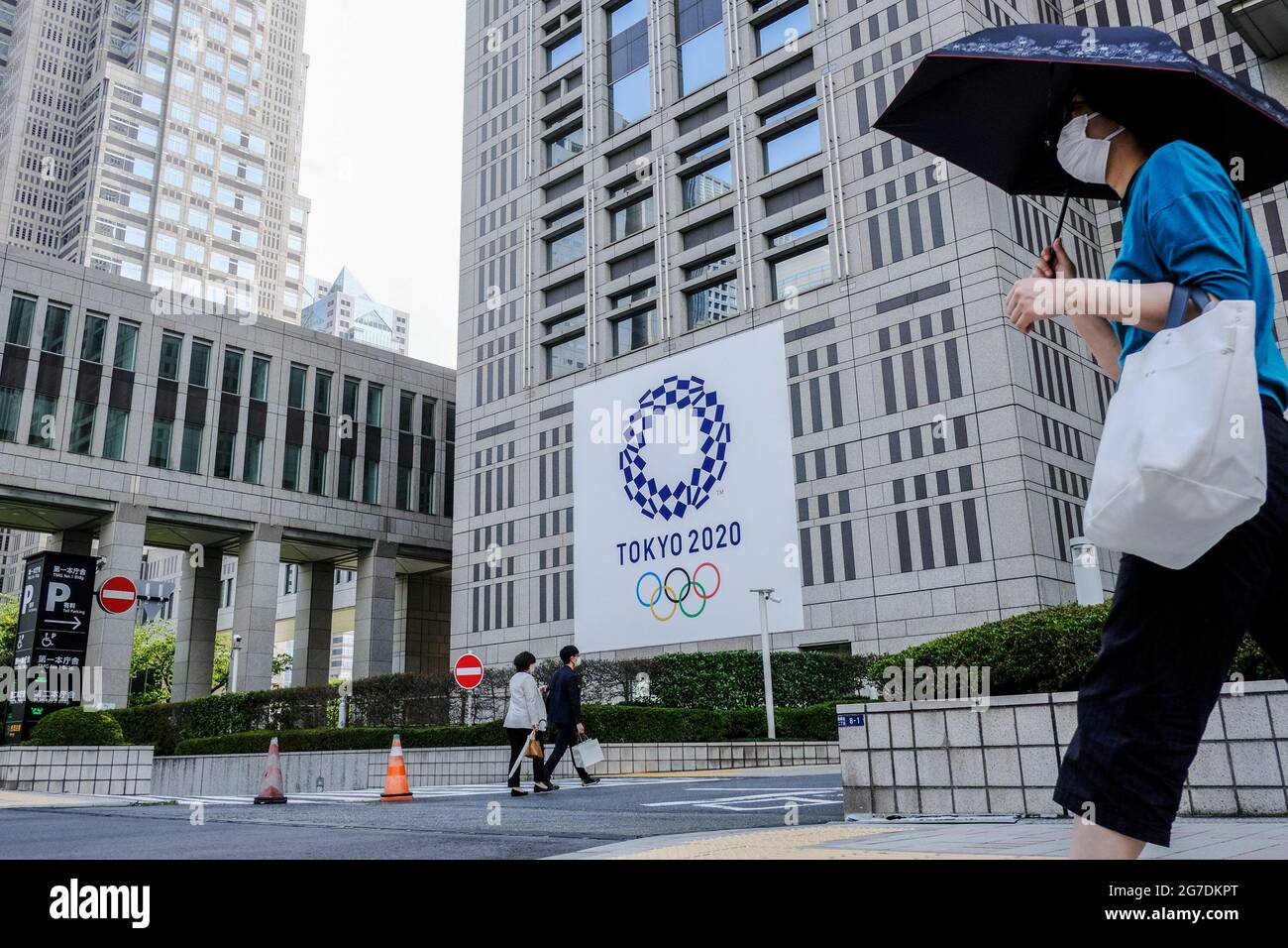 A woman wearing a mask walks past a Tokyo 2020 Olympics banner at the ...