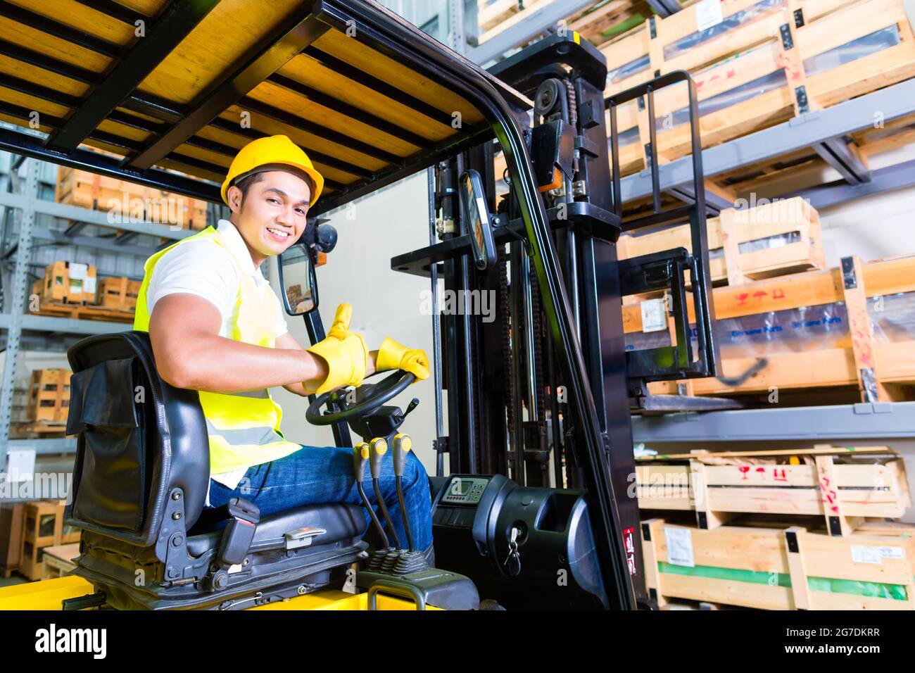 Asian fork lift truck driver lifting pallet in storage warehouse Stock ...