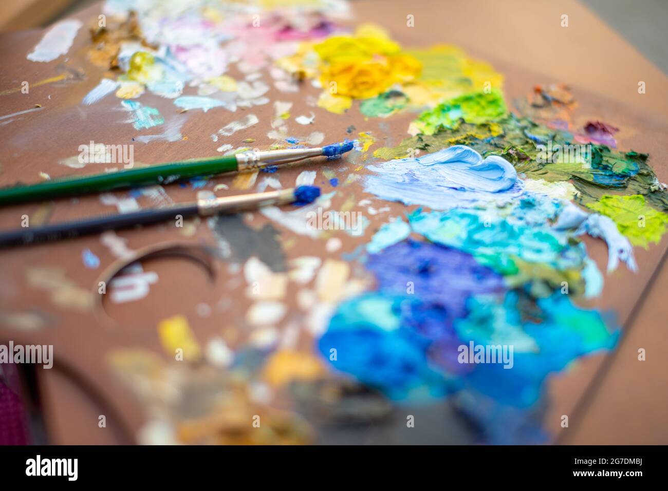 Palette with multi-colored paints and brushes, woman painting picture ...