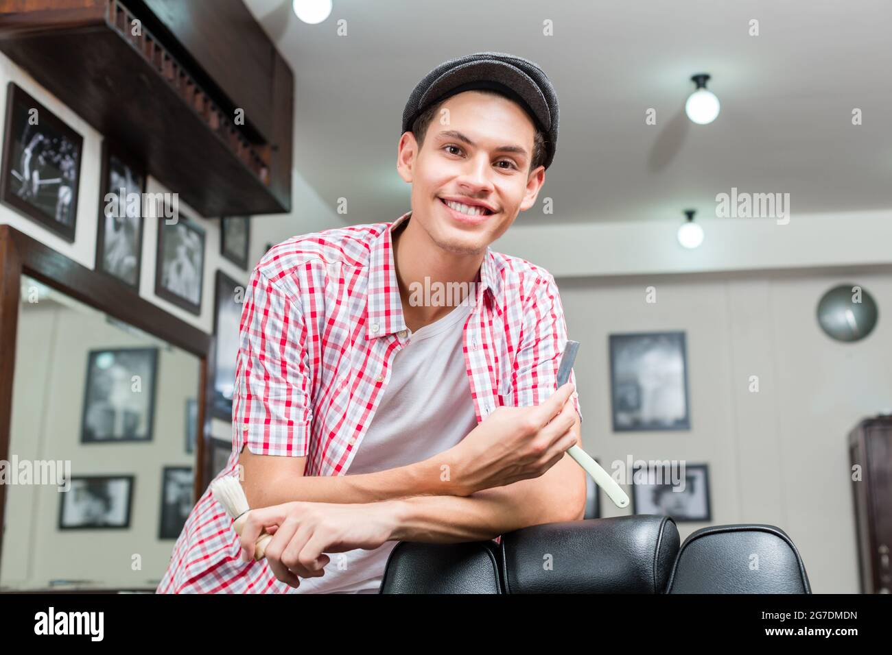 Close-up of smiling professional hairdresser holding straight razor and ...