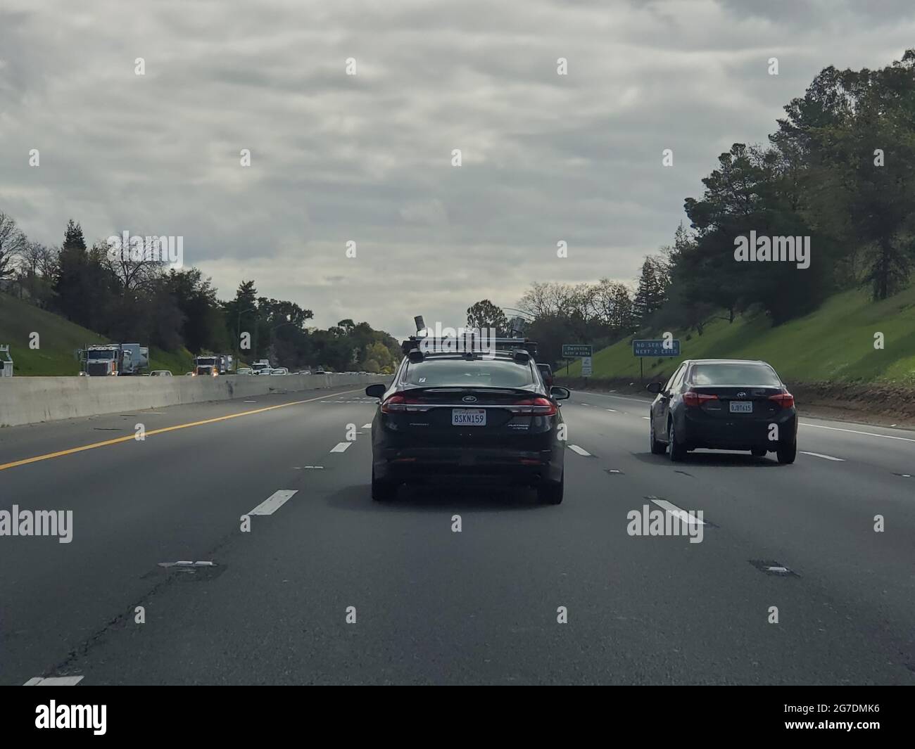A self driving car with a human safety driver is visible traveling on ...