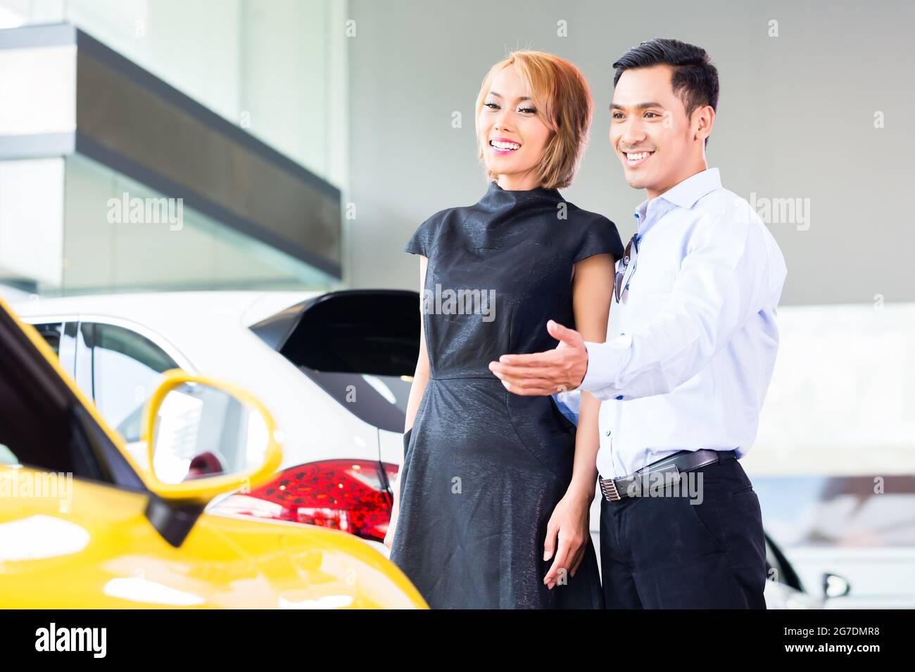 Asian couple choosing luxury sports car in auto dealership Stock Photo ...