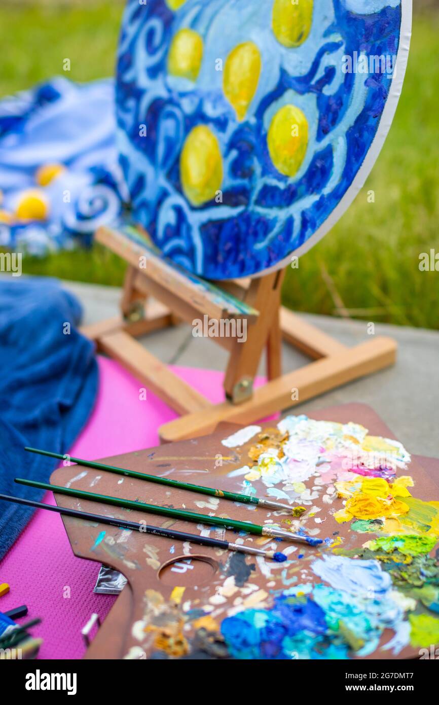 Palette with multi-colored paints and brushes, woman painting picture ...