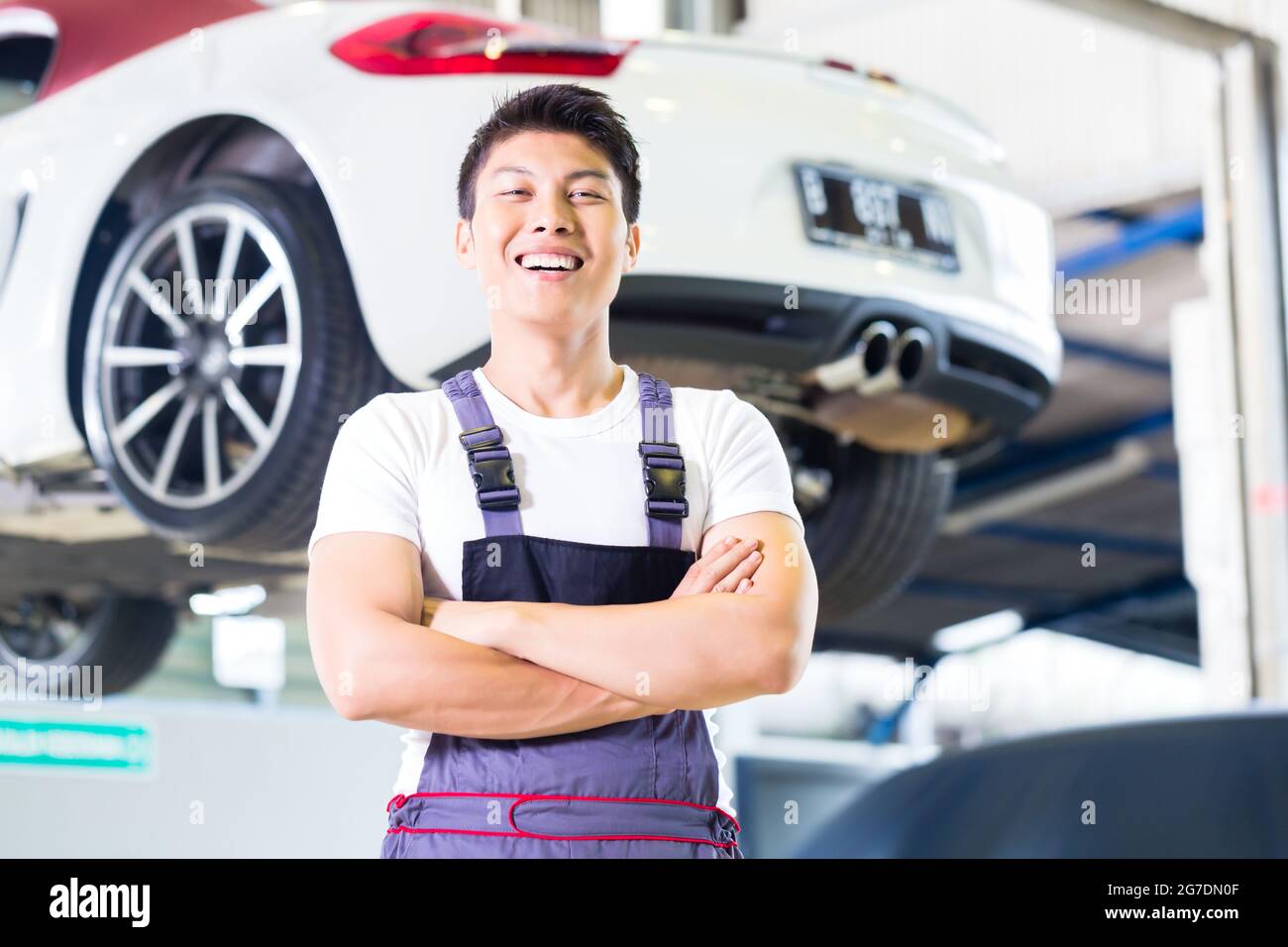 Asian Chinese car mechanic standing in front of luxury car in auto ...