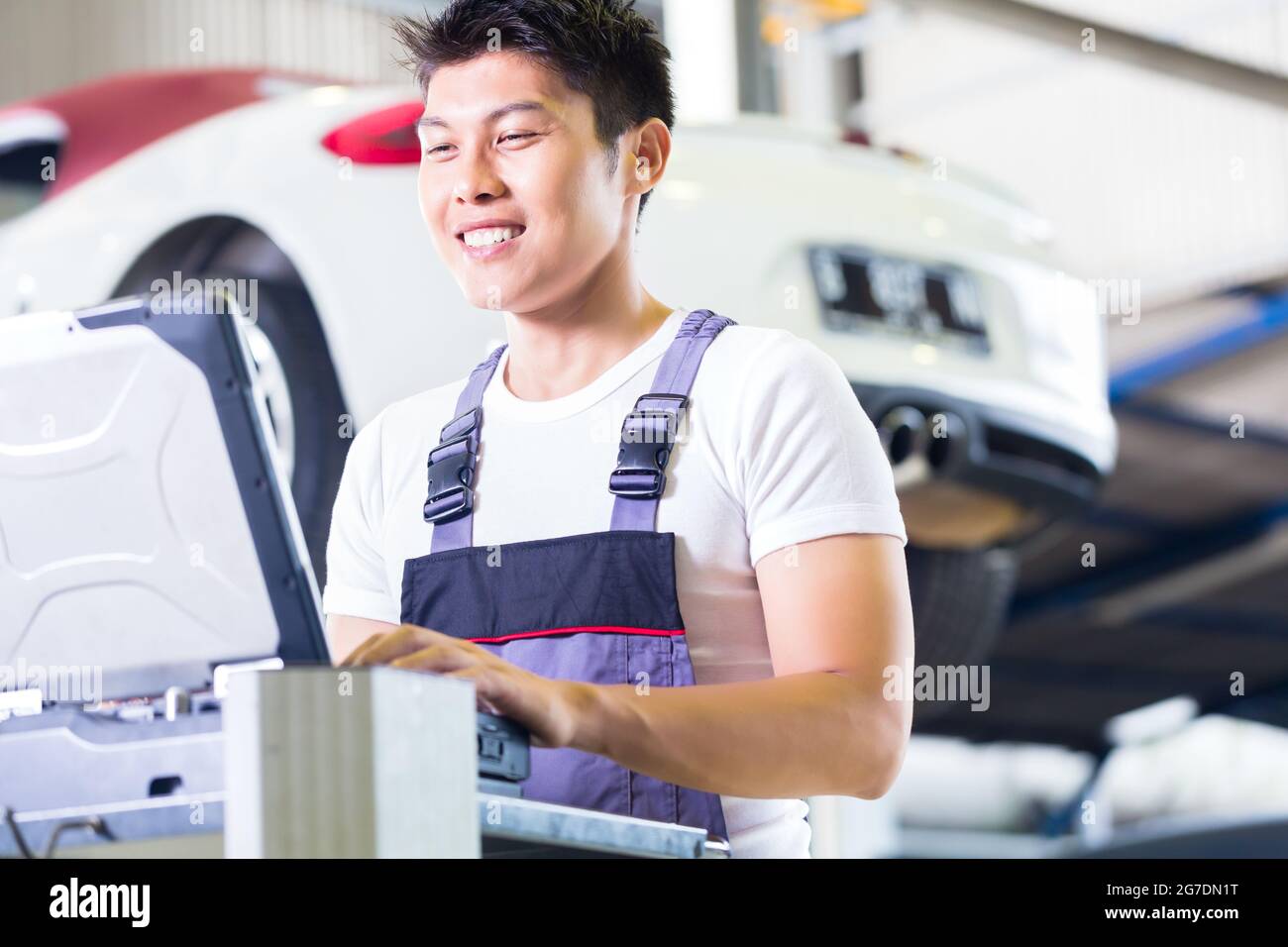 Asian Chinese car mechanic checking auto engine with diagnostics tool ...