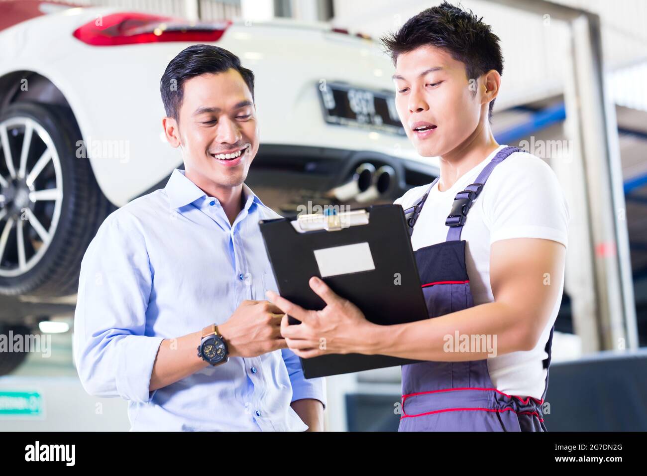Asian Chinese car mechanic with customer going through the maintenance ...