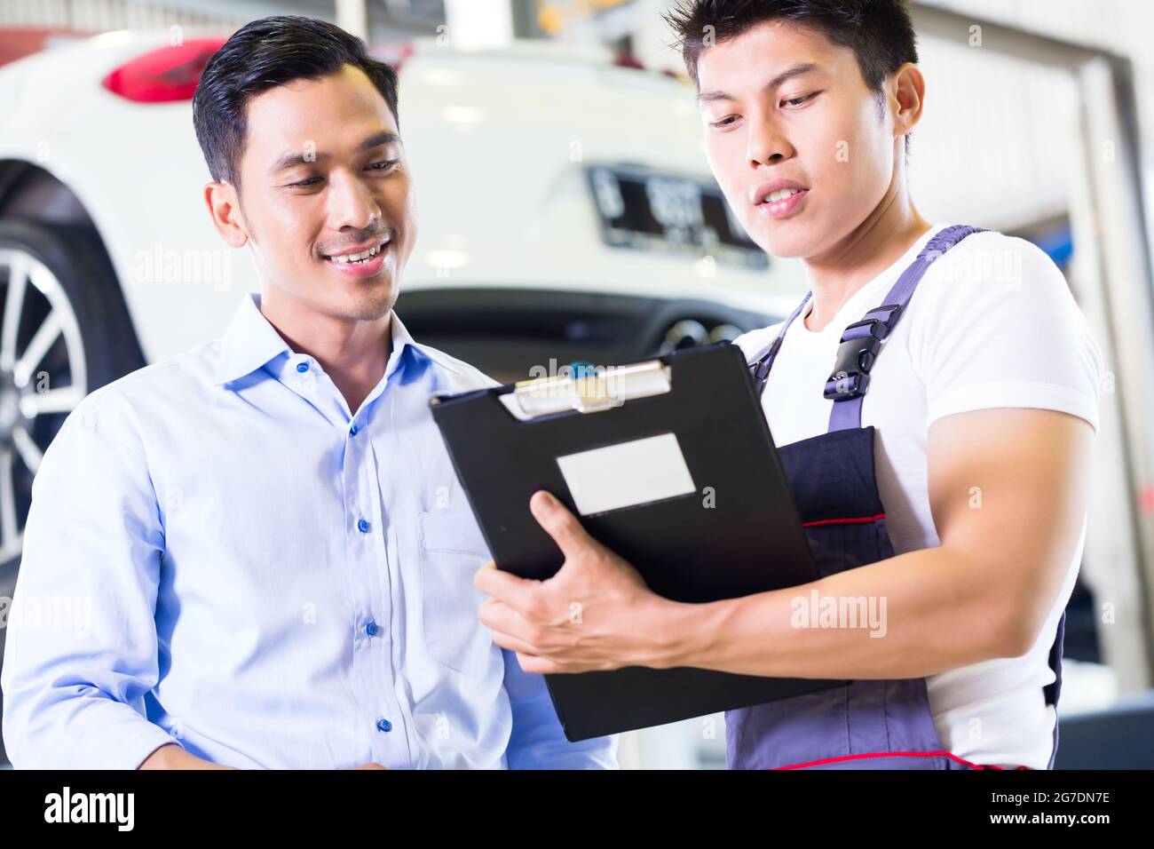 Asian Chinese car mechanic with customer going through the maintenance ...