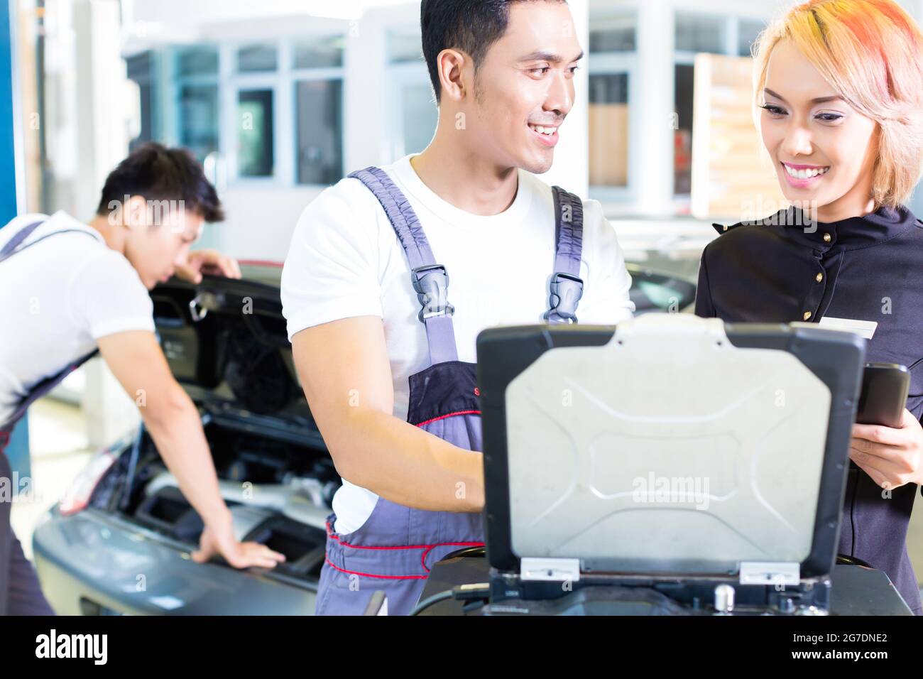 Asian Chinese car mechanic team checking auto engine with diagnostics ...