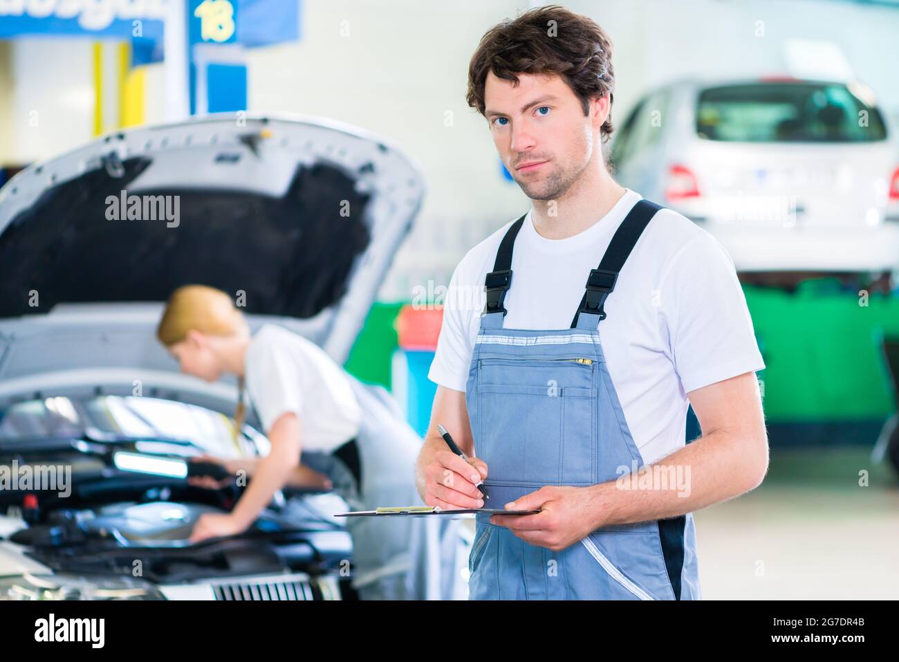 Male and female mechanic team examine car engine with light and ...