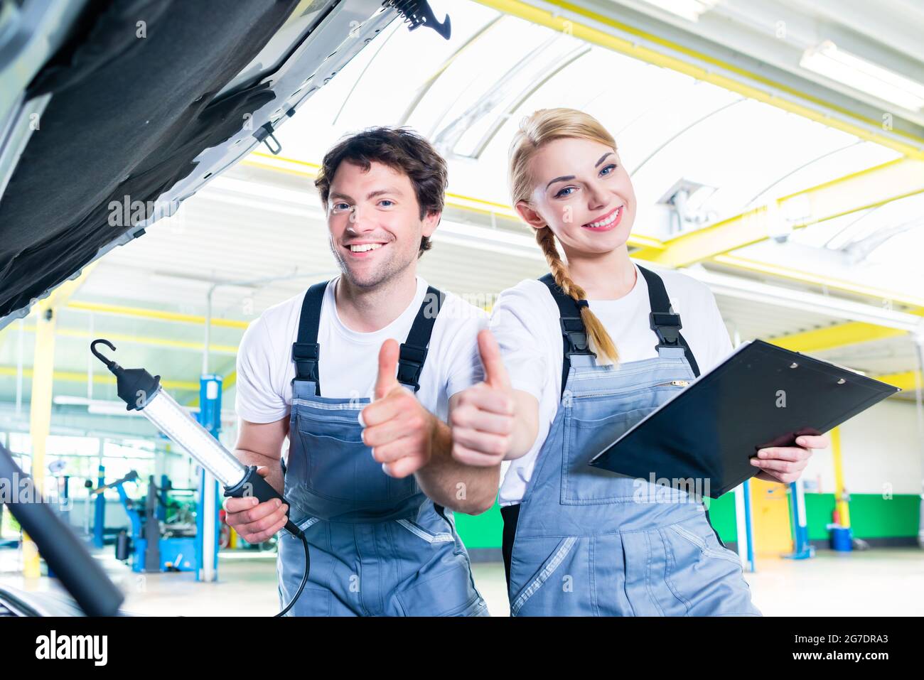 Happy mechanic team working in car workshop Stock Photo - Alamy