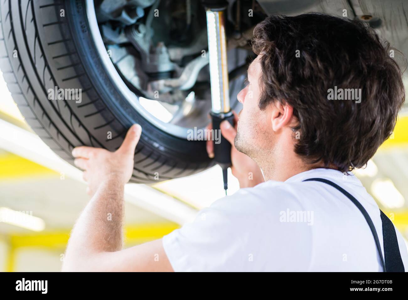 Mechanic working in car workshop on wheel Stock Photo - Alamy
