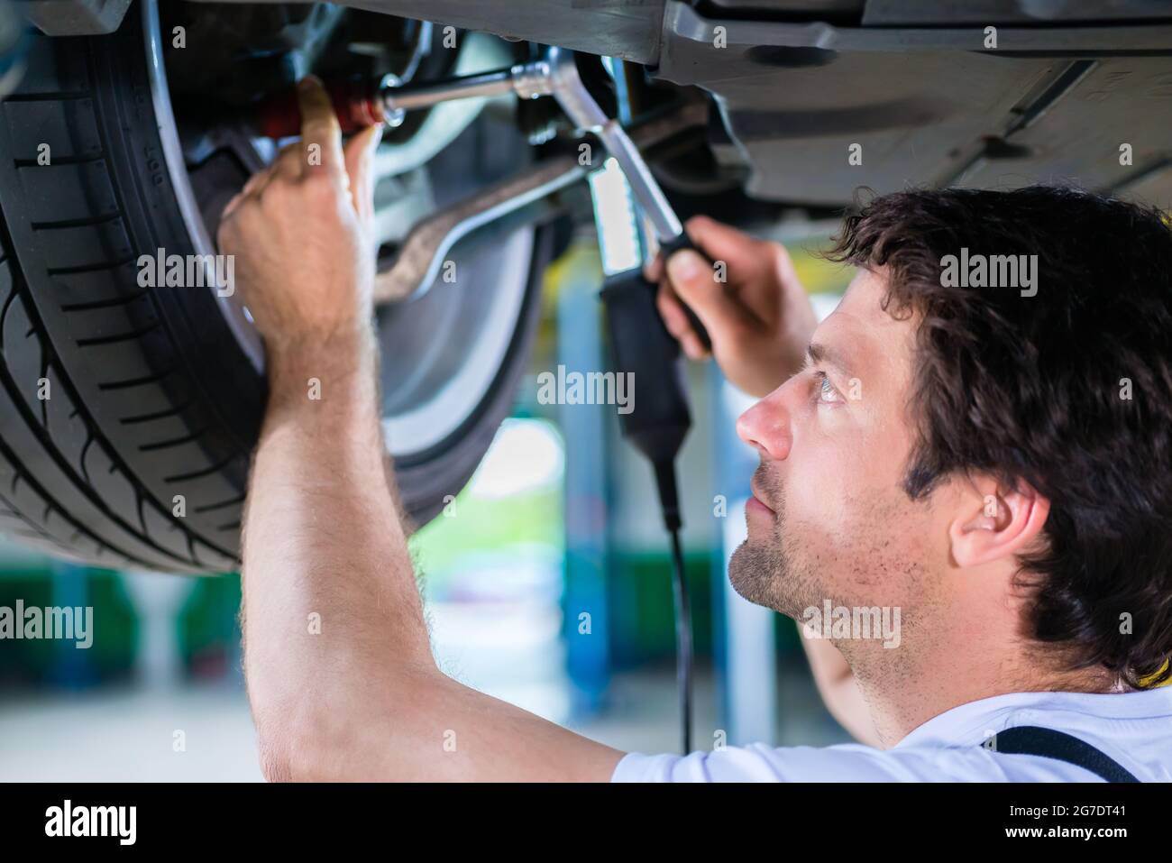 Mechanic working on car wheel in service workshop Stock Photo - Alamy