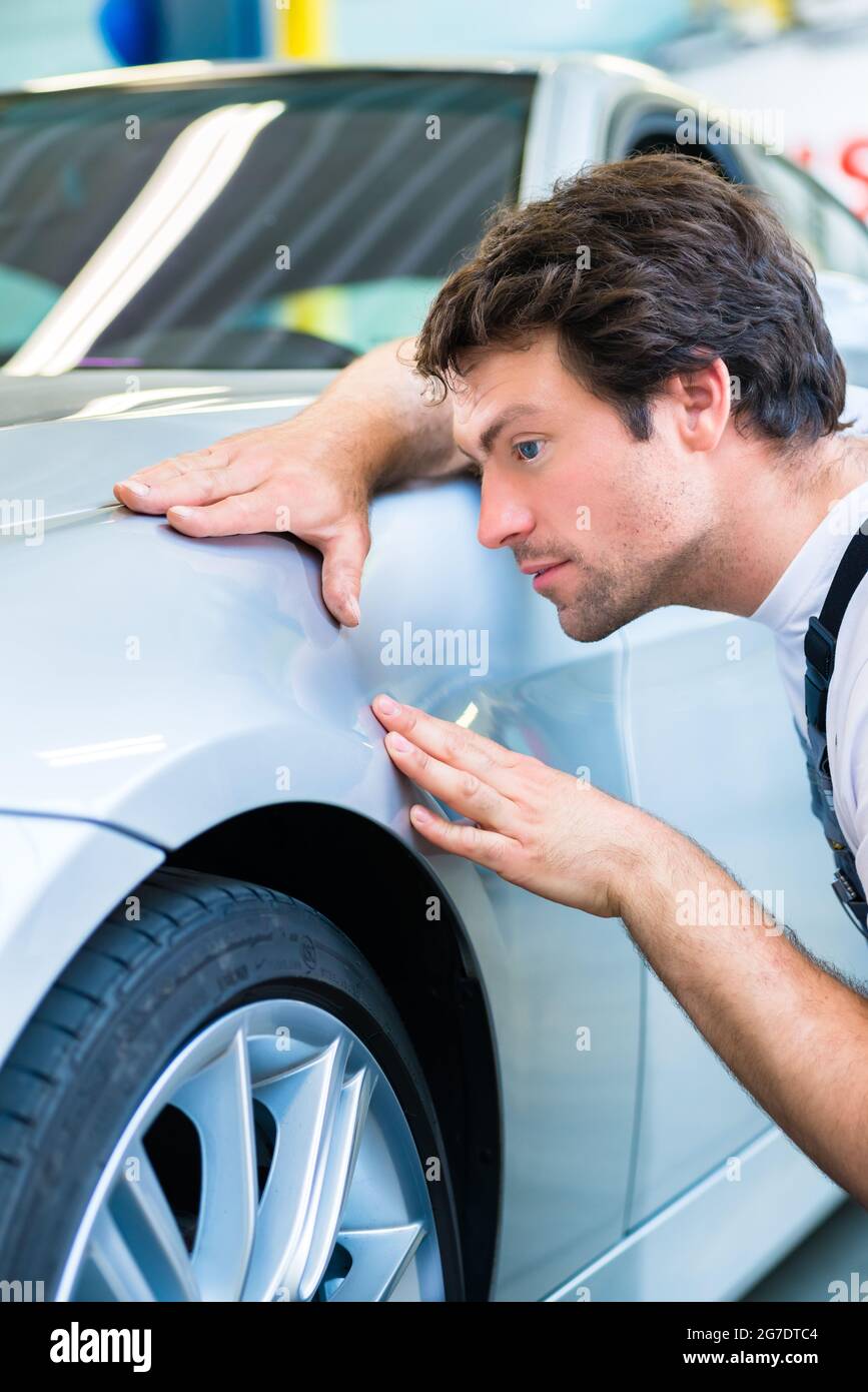 Male mechanic examine car finish on dents or scratches in workshop ...