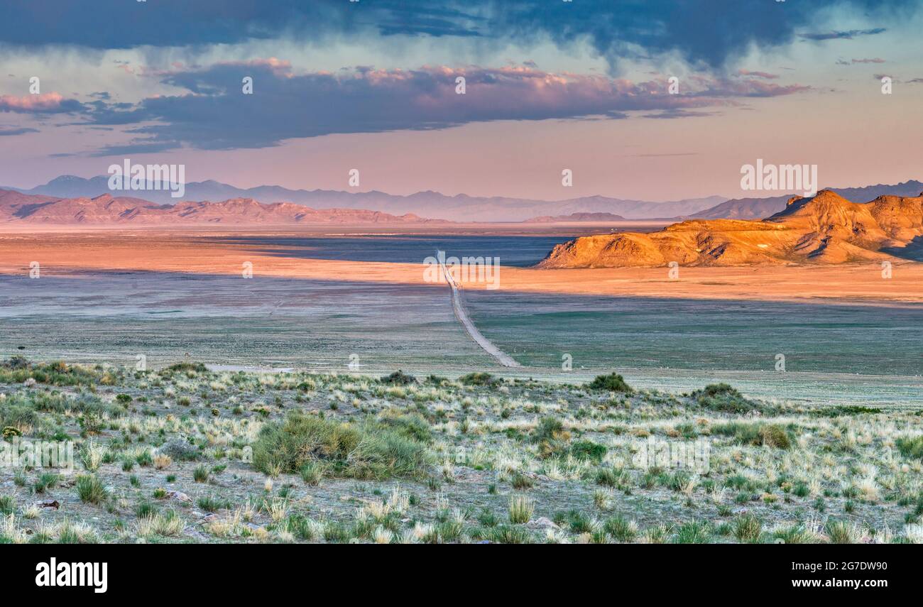 Dirt road crossing Dugway Valley, virga streamers of evaporating rain ...