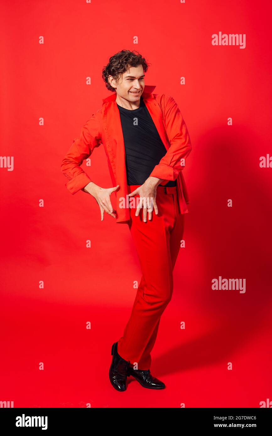 Portrait of a tall handsome man dressed in red shirt posing on the red ...
