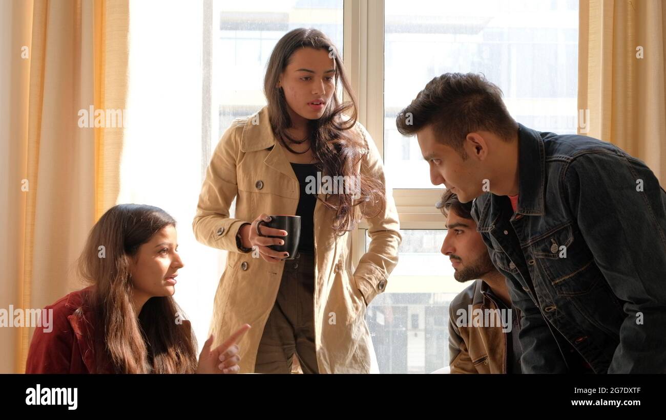 Group of smiling young Indian males and females happily talking to each ...