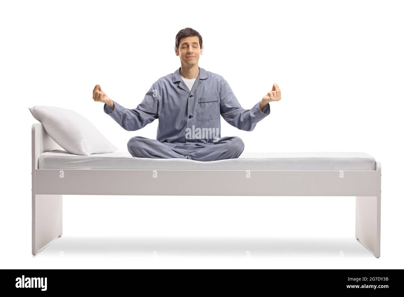 Man wearing pajamas and practicing yoga on a bed isolated on white ...