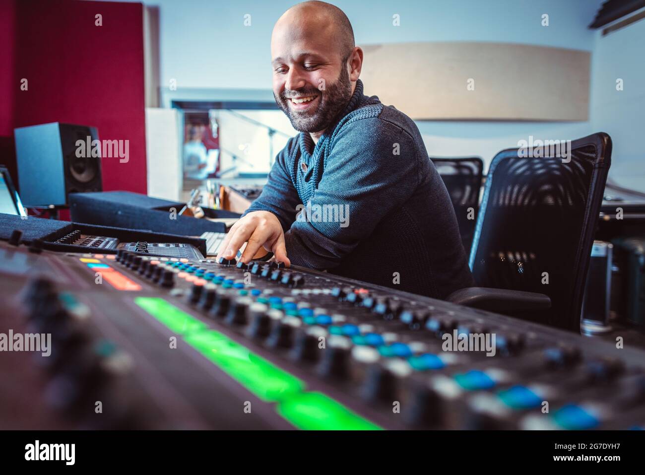 Sound engineer mixing a song in his studio pushing a fader and the ...