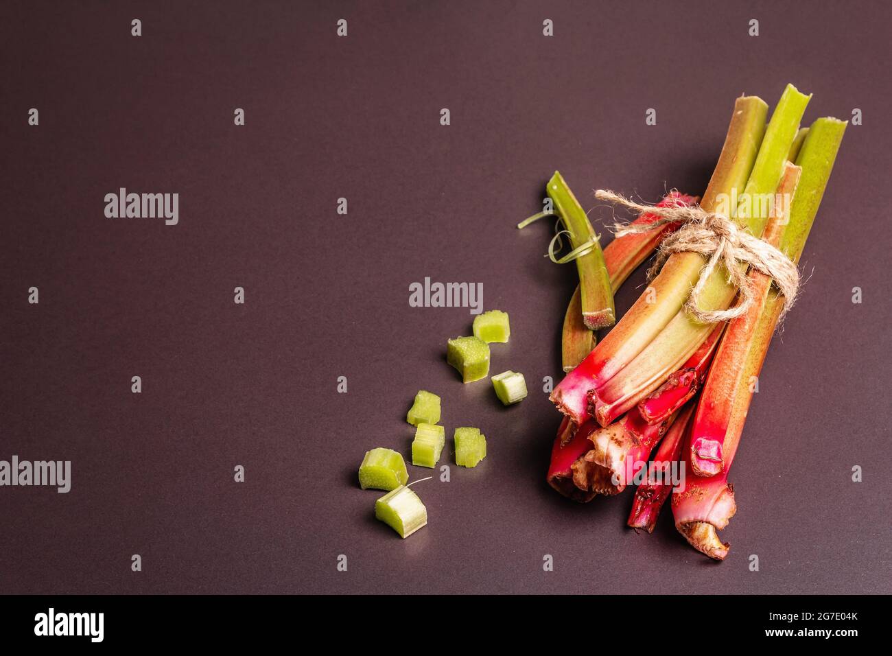 Fresh rhubarb stalks and cut pieces on a black stone background ...