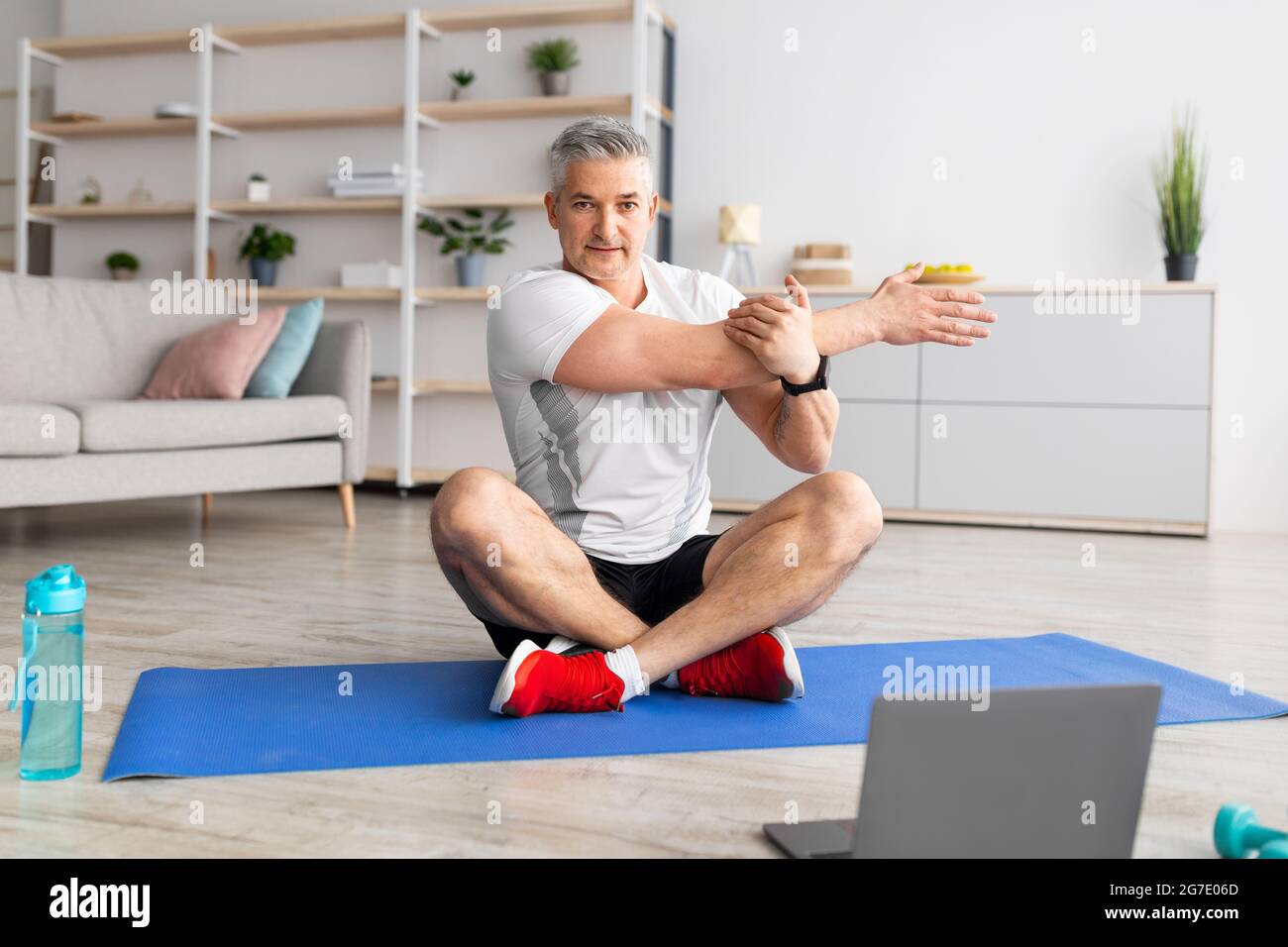 Sport in mature age. Happy middle-aged man doing stretching exercises ...