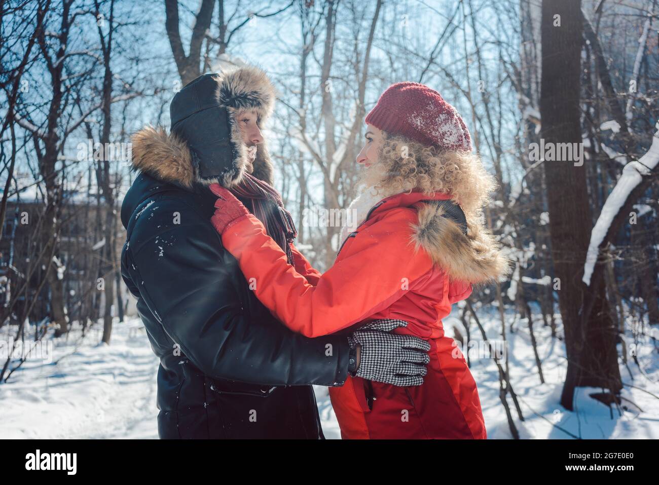 Couple hugging being in love on a cold winter day in the snow looking ...