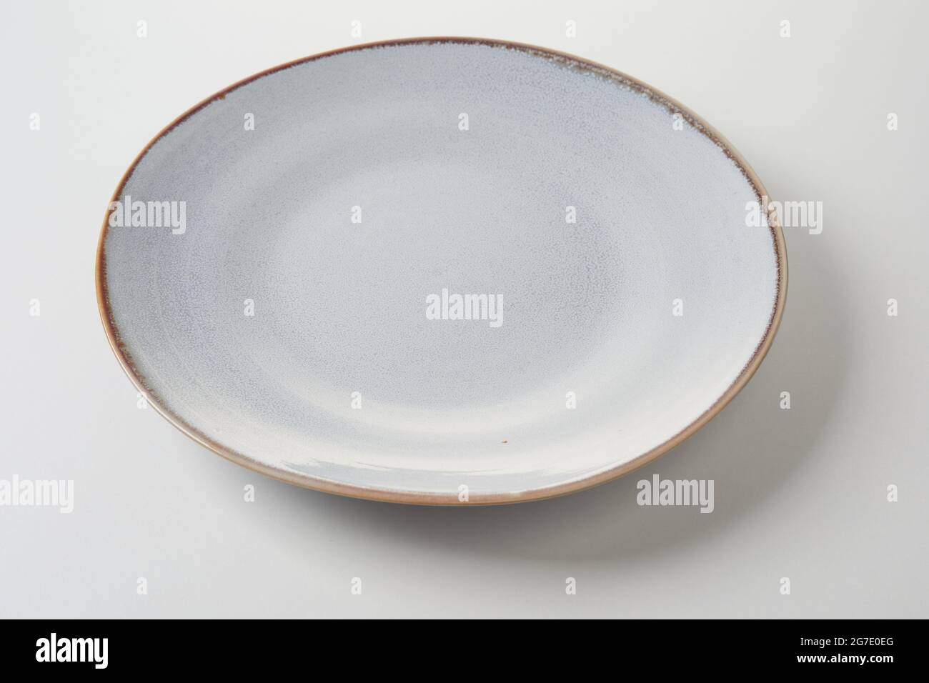Empty clean generic white pottery plate or disg with narrow brown rim ...