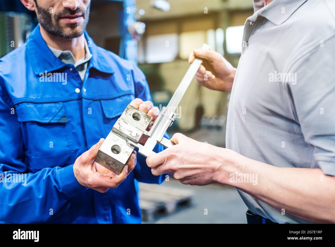 Two workers checking measurements of work piece in the factory being ...