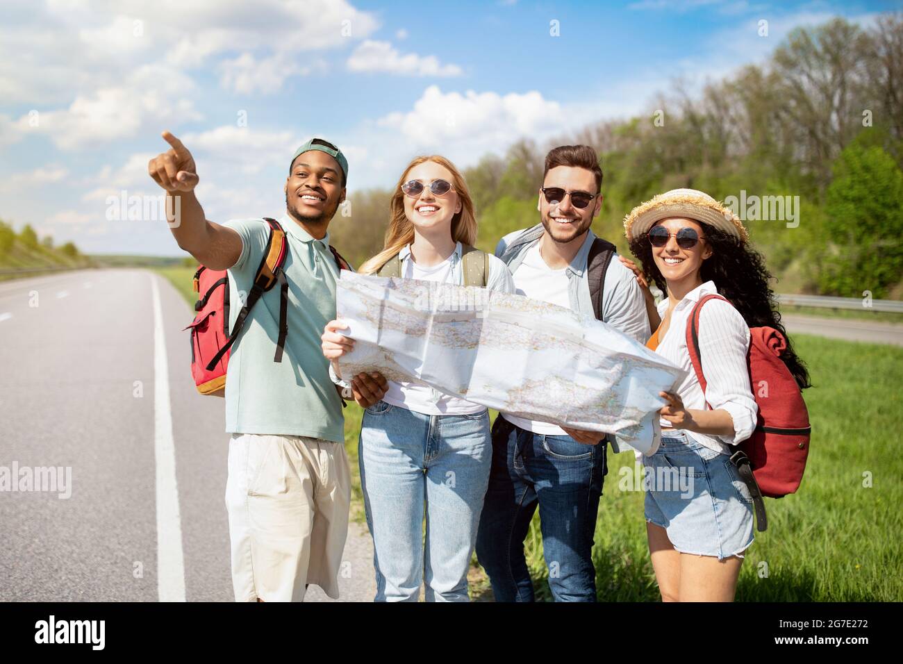 Group of multiethnic friends checking map, choosing route during road ...