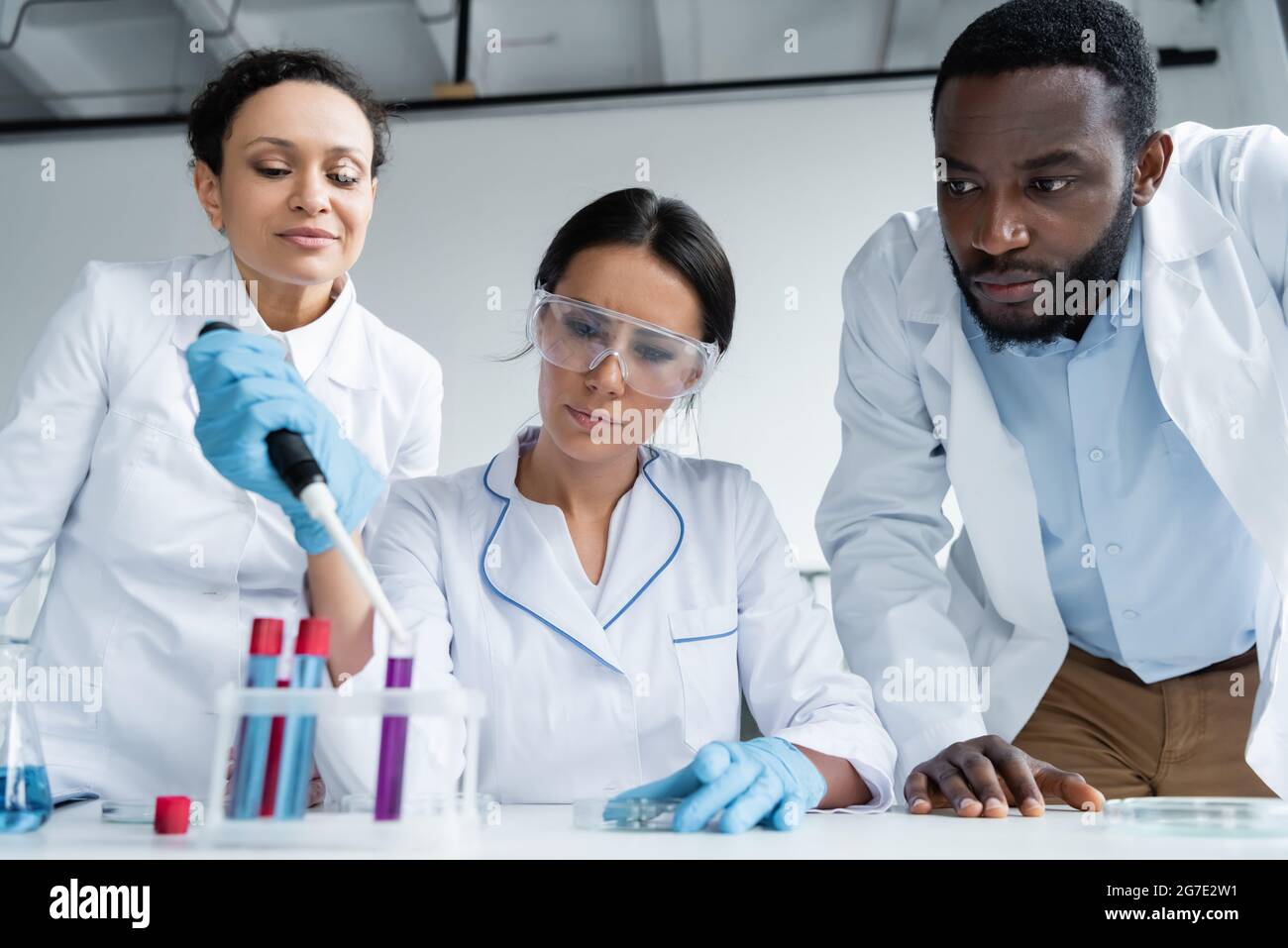 African american scientists looking at colleague making experiment in ...