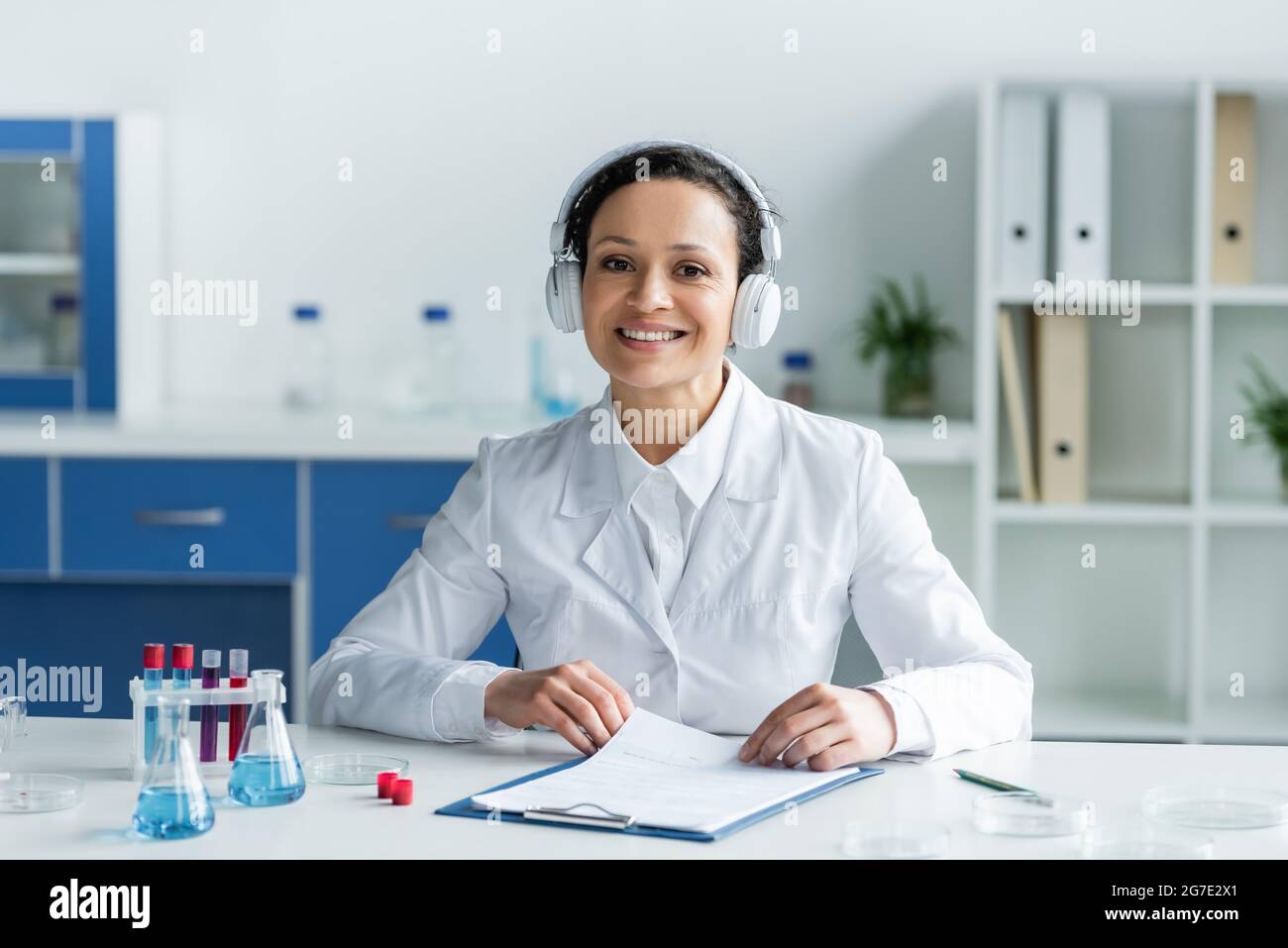 Smiling african american scientist in headphones looking at camera near ...