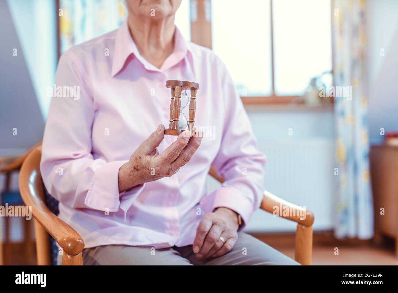 Senior in nursing home holding a hourglass - time is running up quickly ...