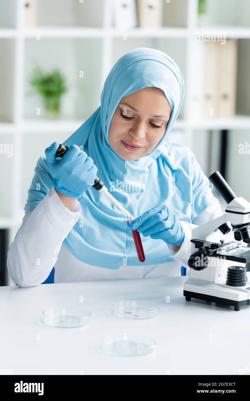 Muslim scientist working with electronic pipette and blood sample near ...