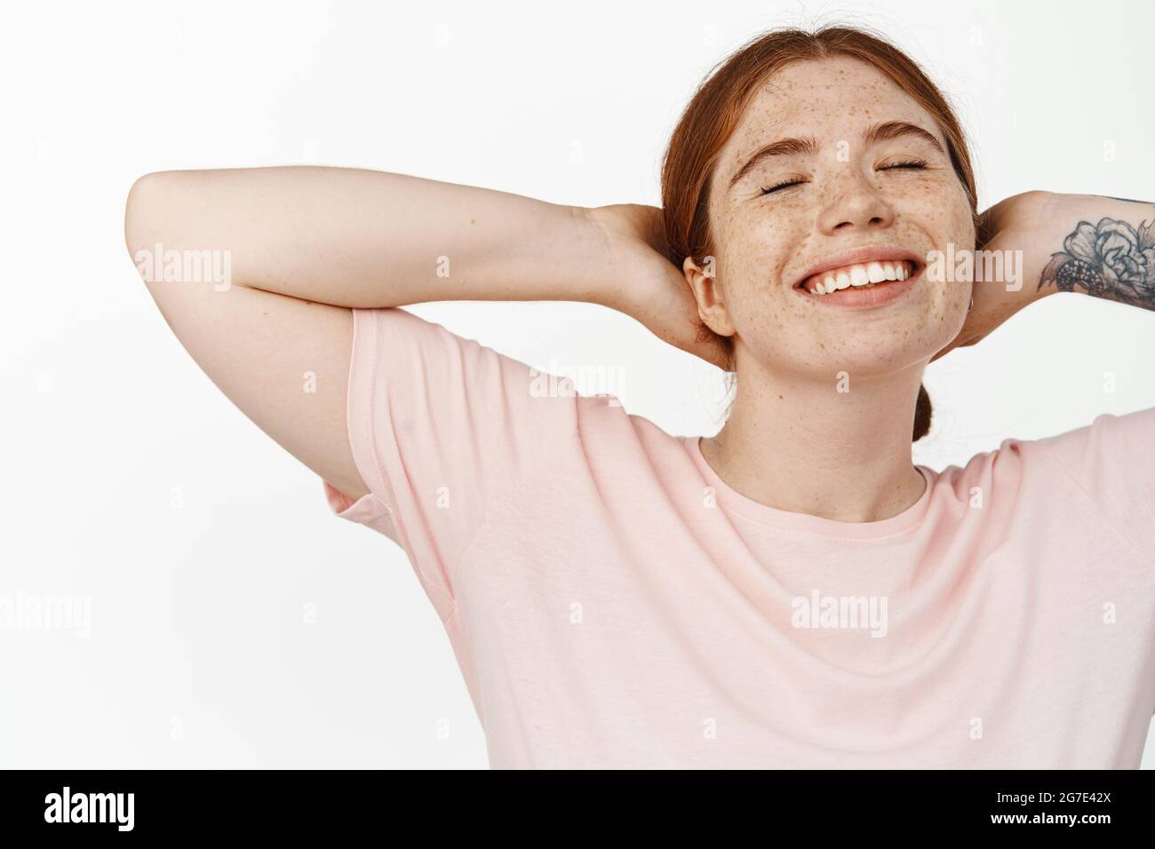 Close up portrait of carefree ginger girl resting, lying with hands ...
