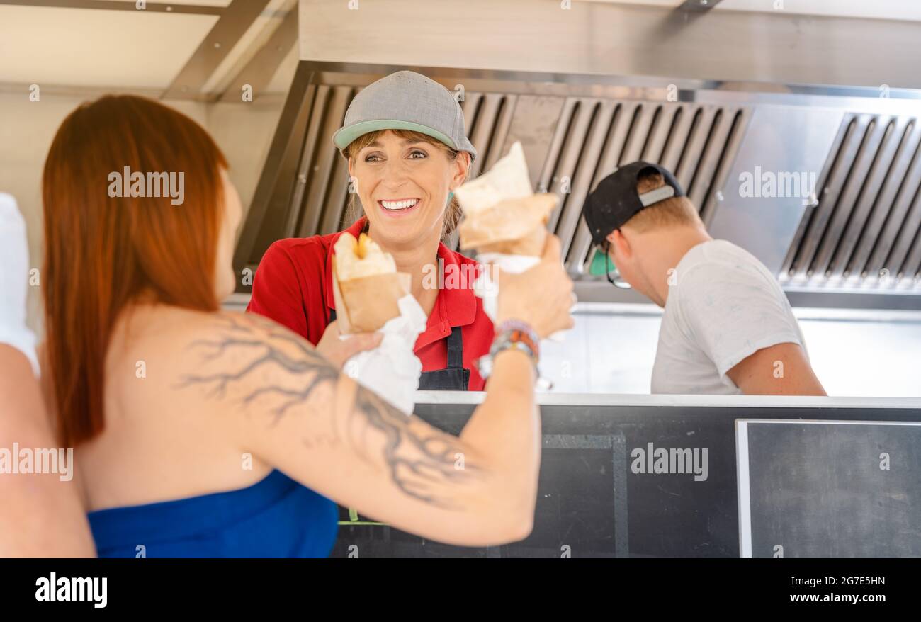 Customers of a food truck receiving their meal from a friendly service ...