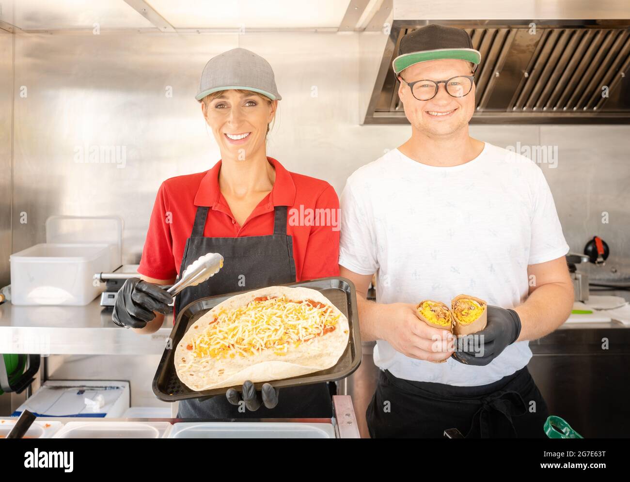 Woman and man chefs showing a meal they prepared in a food truck ...