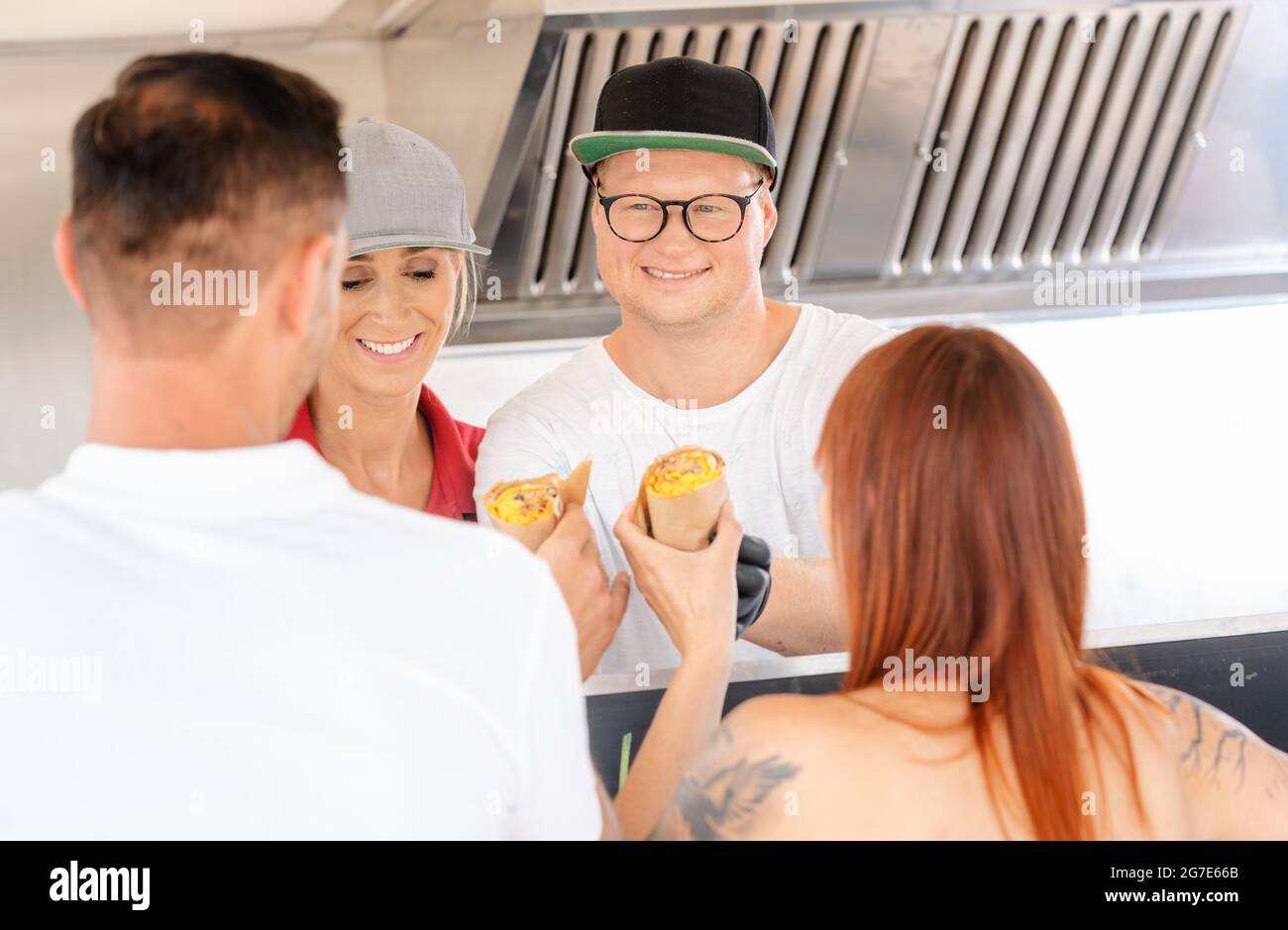 Chefs giving Burritos to customers of food truck waiting in line Stock ...