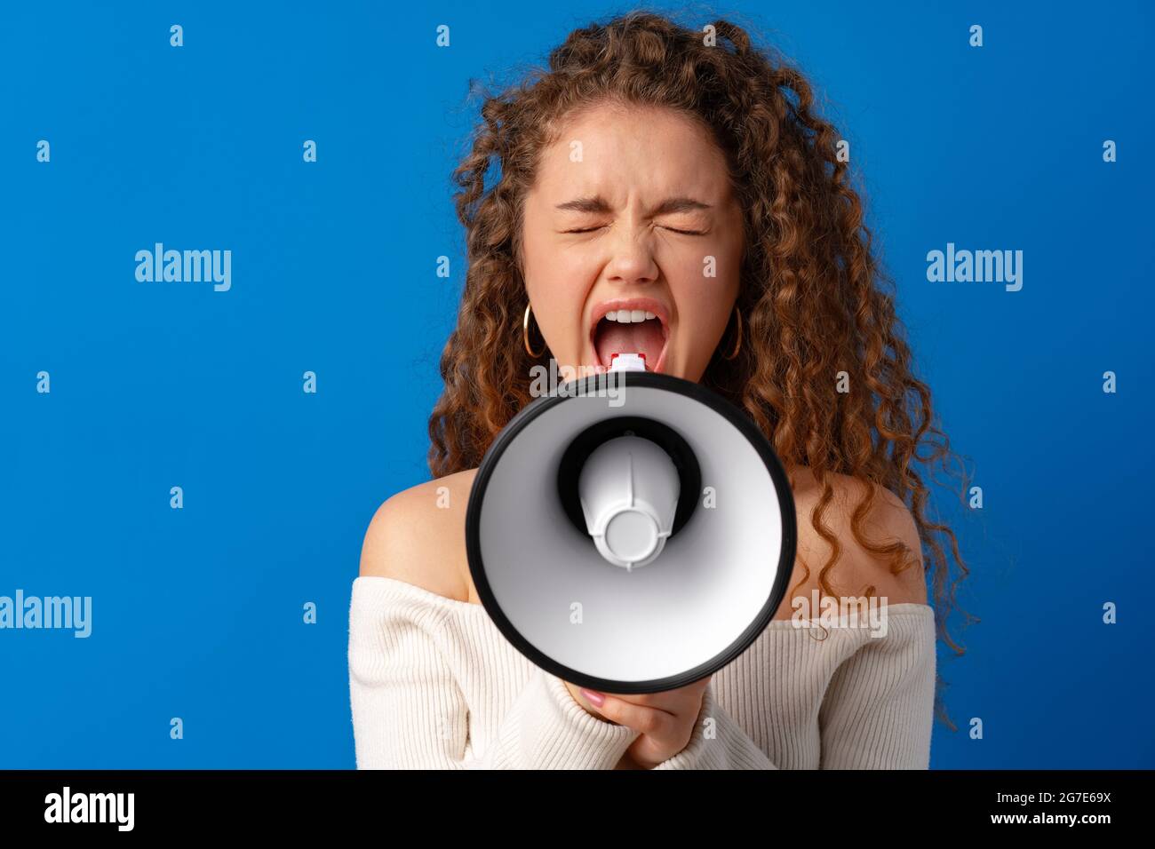 Young smiling expressive caucasian woman shout in megaphone against ...