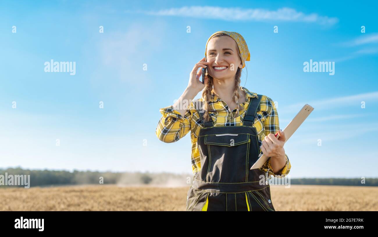 Farmer using her phone on a grain field during harvest Stock Photo - Alamy