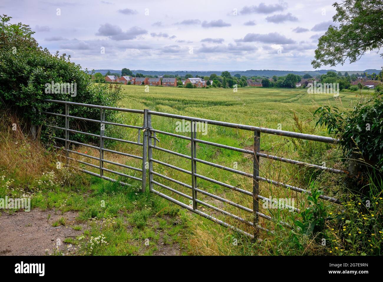 Through a metal farm gate, from the edge of Bramcote Woods, a view a ...