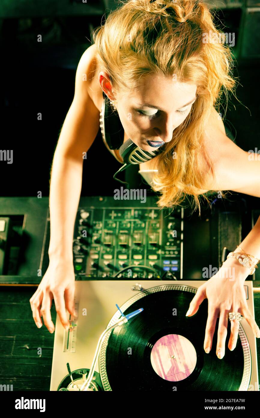 Female DJ at the turntable in a club, with mixer and old school record ...