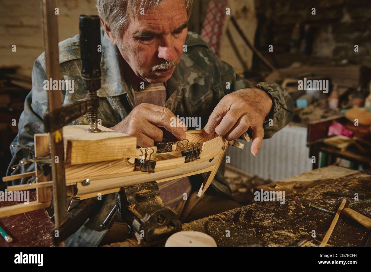 Carpenter sticks a wooden part on a wooden ship. Craftsman in workshop ...