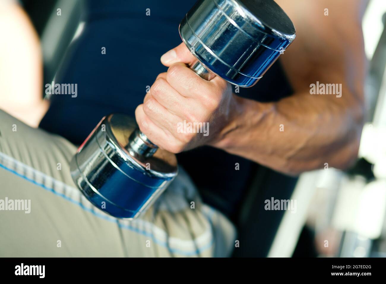Strong man with dumbbells; focus on hand and dumbbell Stock Photo - Alamy