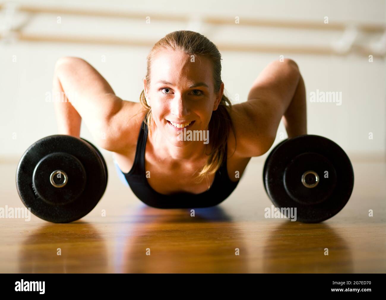 Powerful lady doing push-ups on dumbbells. training her muscles Stock ...